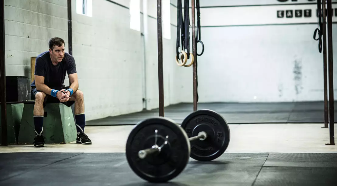 Uomo Stanco, A Riposo In Palestra Con Il Bilanciere