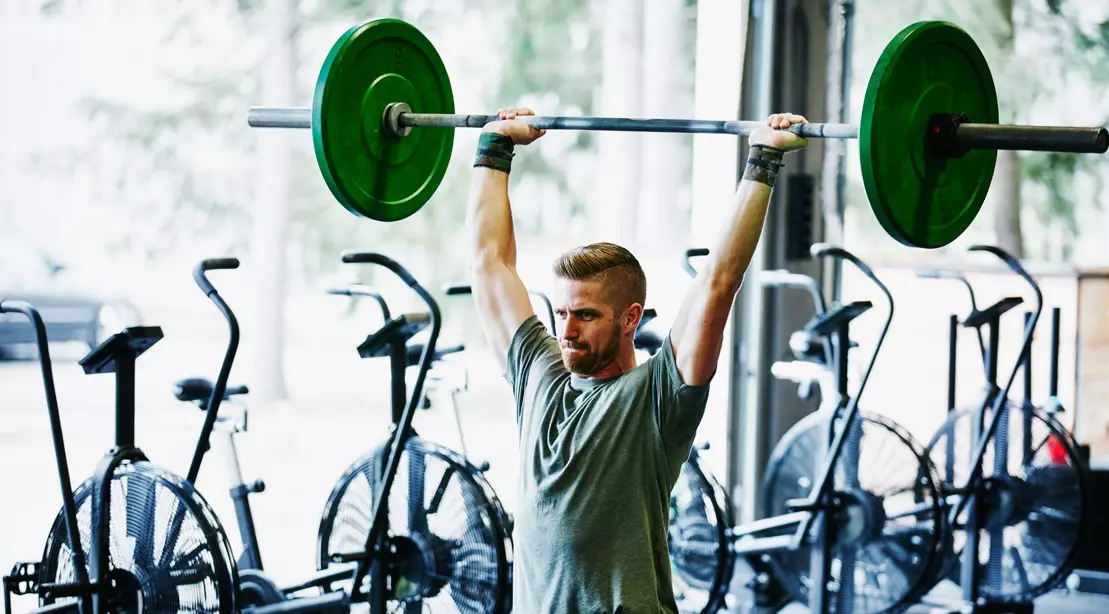 Man dy't in overhead barbell-parse-oefening útfiert