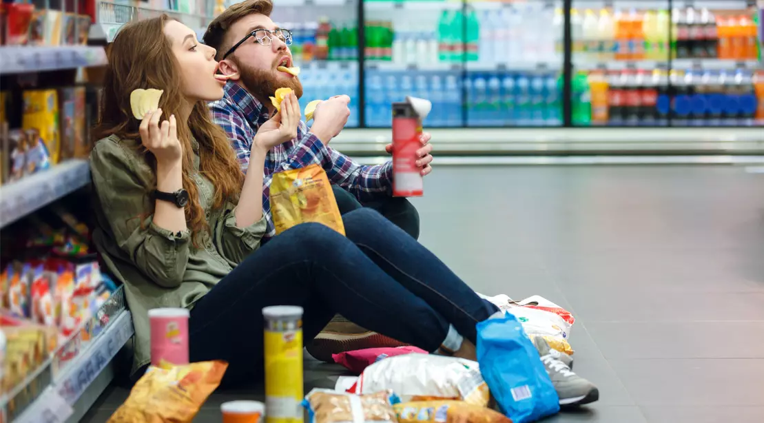 Garoto e garota comendo junk food no chão do supermercado