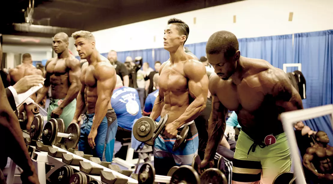 Bodybuilders in een bodybuilding-wedstrijd die halters optilt voor een spiegel