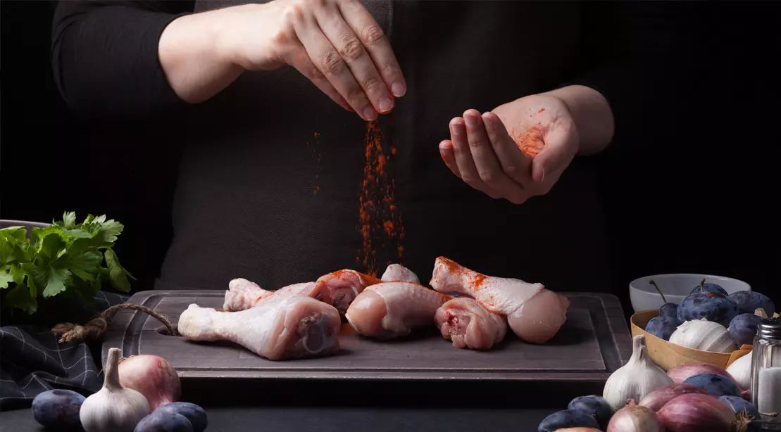 Person-Hands-Seasoning-Chicken-DrumSticks-With-Red-Seasoning