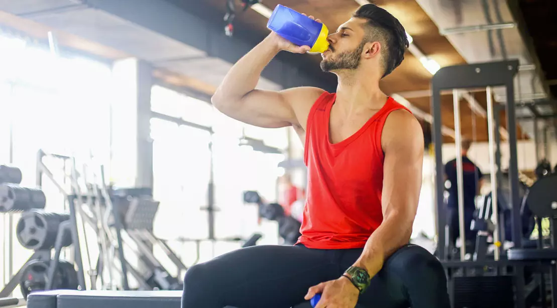 Homme buvant un shake protéiné dans la salle de sport