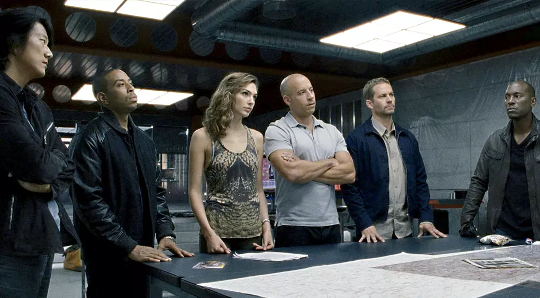 Schauspieler Sang Kang Ludacris Gal Gadot Vin Diesel Paul Walker und Tyrese Gibson stehen in „Fast and Furious 6“ um einen Tisch herum