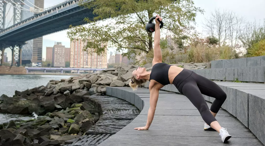 L'entrenadora Sarah realitza una posada de peu amb Kettlebell a DUMBO NYC com a part de l'entrenament de Kettlebell per a principiants