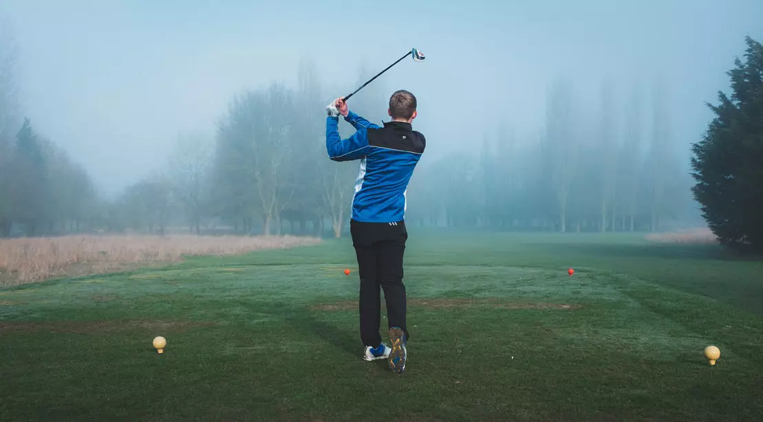 Dumanly günde golf oýnaýan kostýum geýen Golfer, golf şikesini almak mümkinçiligini artdyrýar