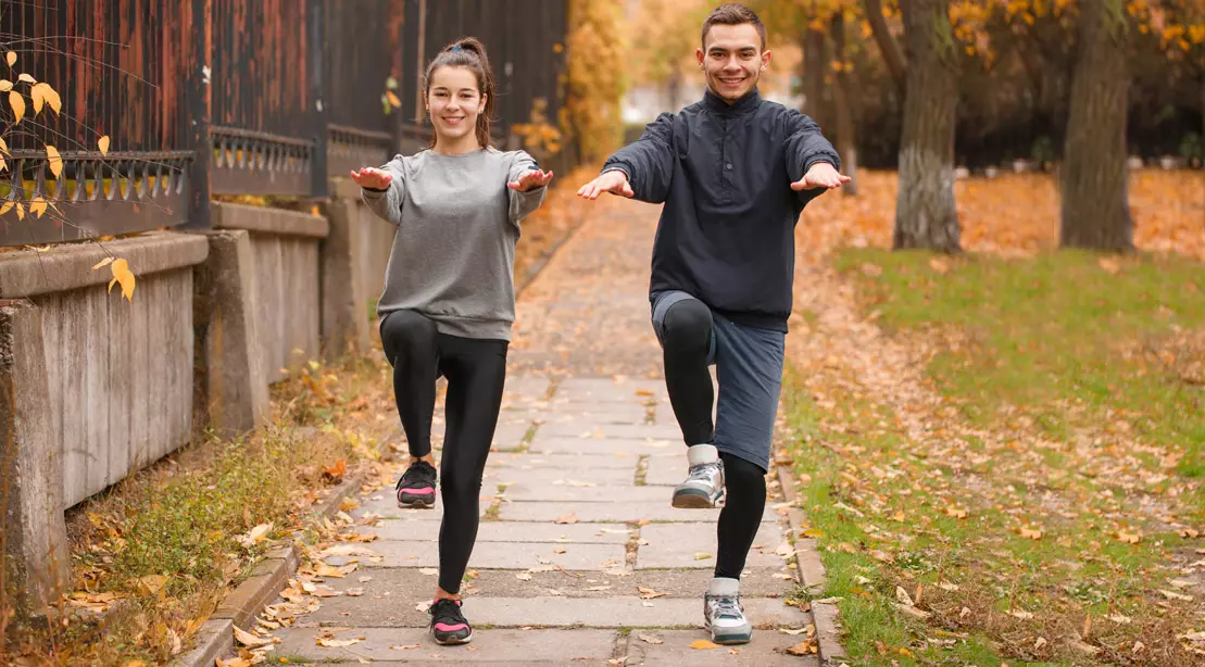 Fitnesspaar met scheenbeenspalken balancerend op één been