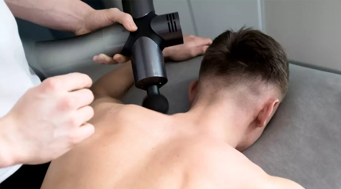 Masseuse-Using-Massage-Gun-On-Shoulder