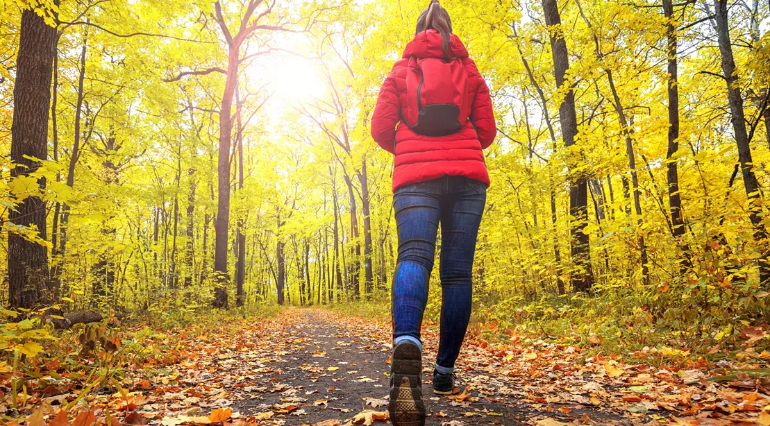 Ragazza con la giacca gonfia che cammina attraverso il parco durante l'autunno