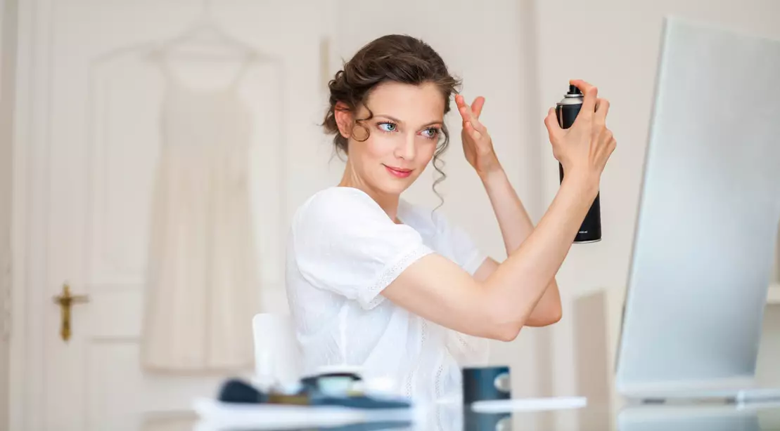 Mujer rociando laca para el cabello