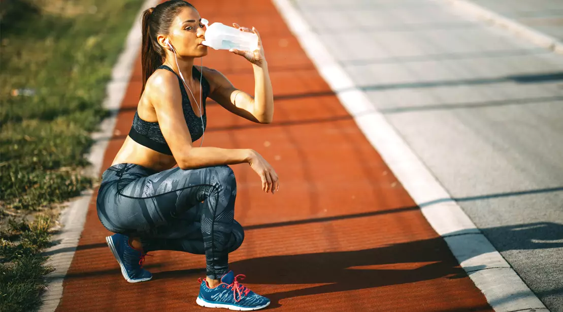 Dievča-Kľačiac-Dole-Drinking-Proteín-Shake-on-Track