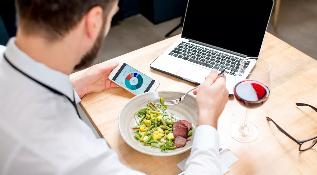 Man äter en sallad på jobbet och räknar sina kalorier och spårar sina makron