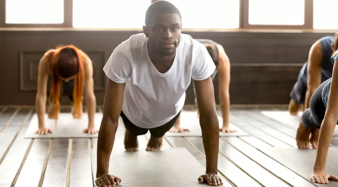 Hombre negro en clase de yoga realizando flexiones