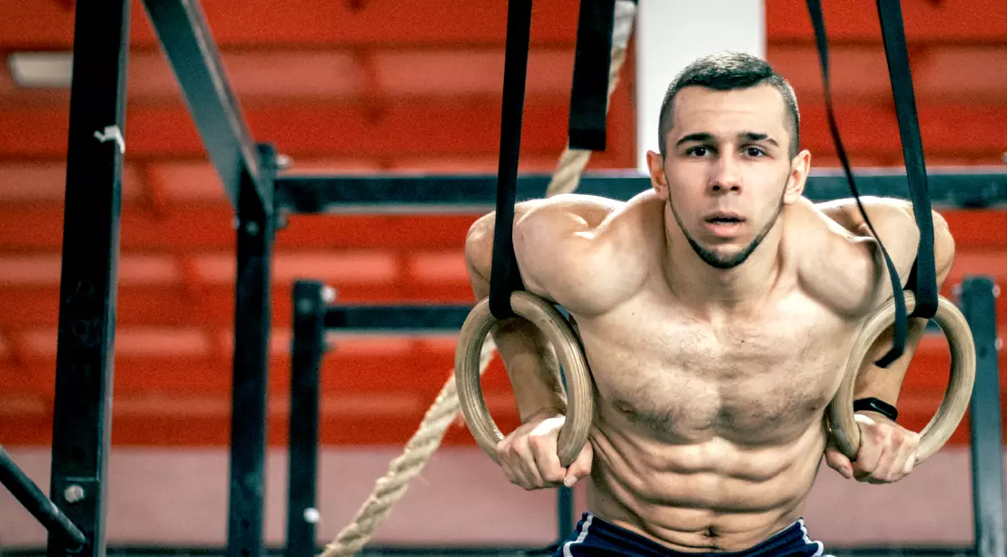 Muscular-Male-Gymnast-Performing-Ring-Chest-Flye