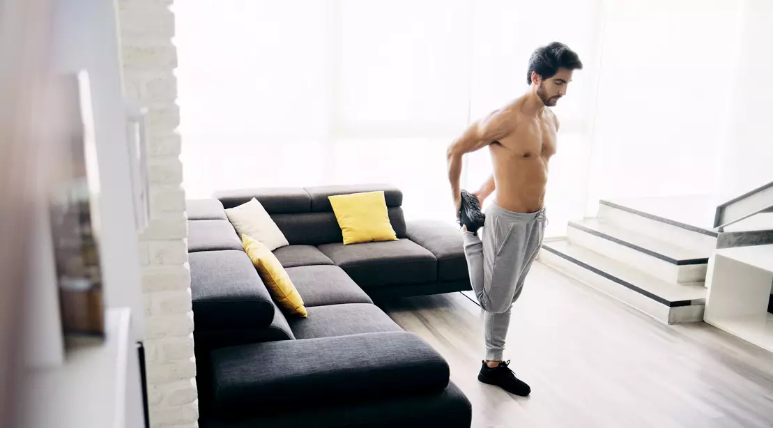 Man-Stretching-Quads-In-Home-Living Room