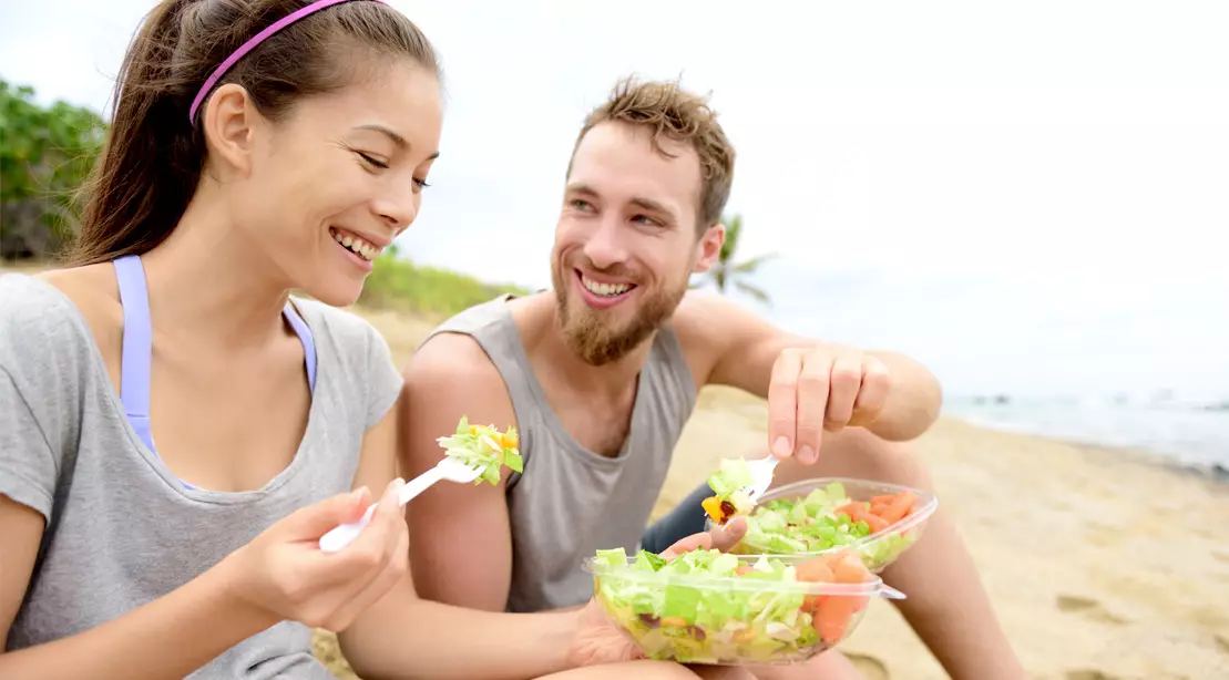 Pasangan sehat sing sehat mangan salad ing pantai