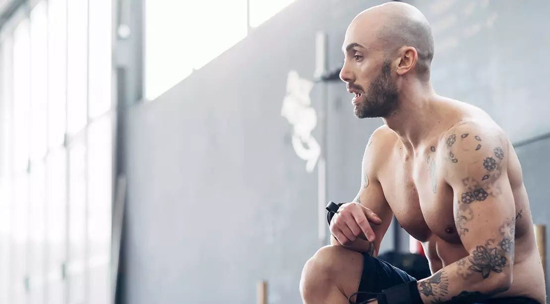 Retrato de homem tatuado na academia olhando para longe