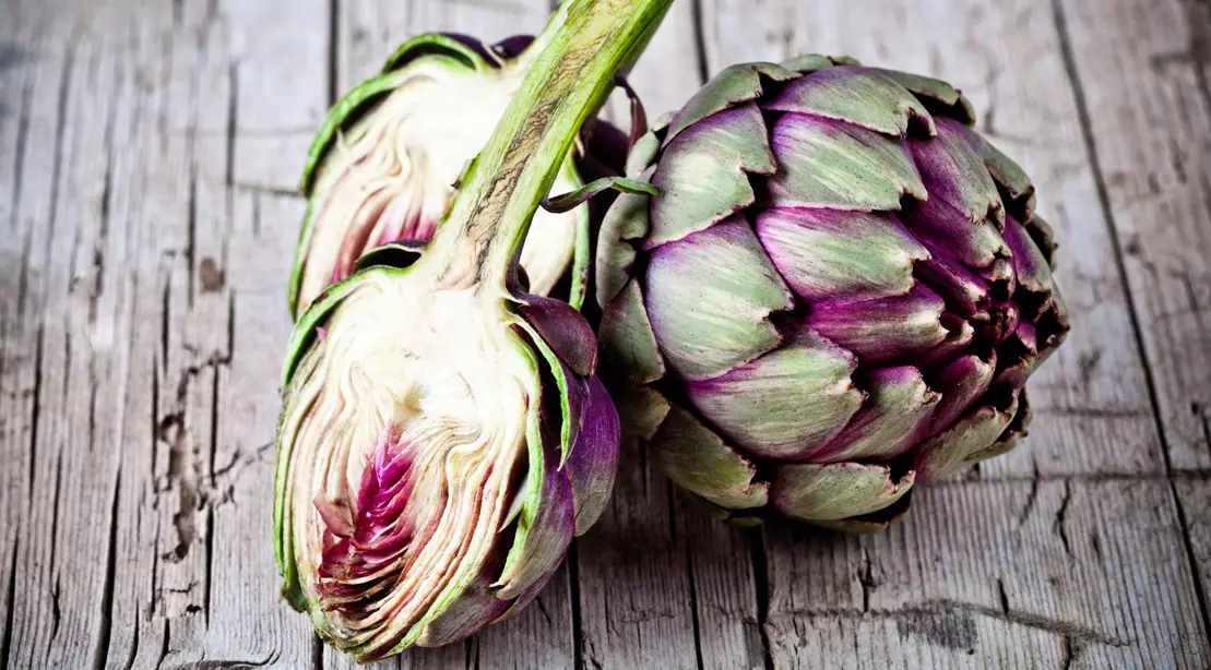 Artichoke yang mengandung pobiotik dipotong dua di atas meja kayu