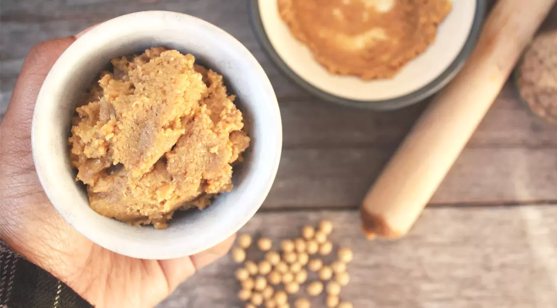 Persoon die een kom met probiotische gevulde miso-pasta vasthoudt die goed is voor je darmgezondheid