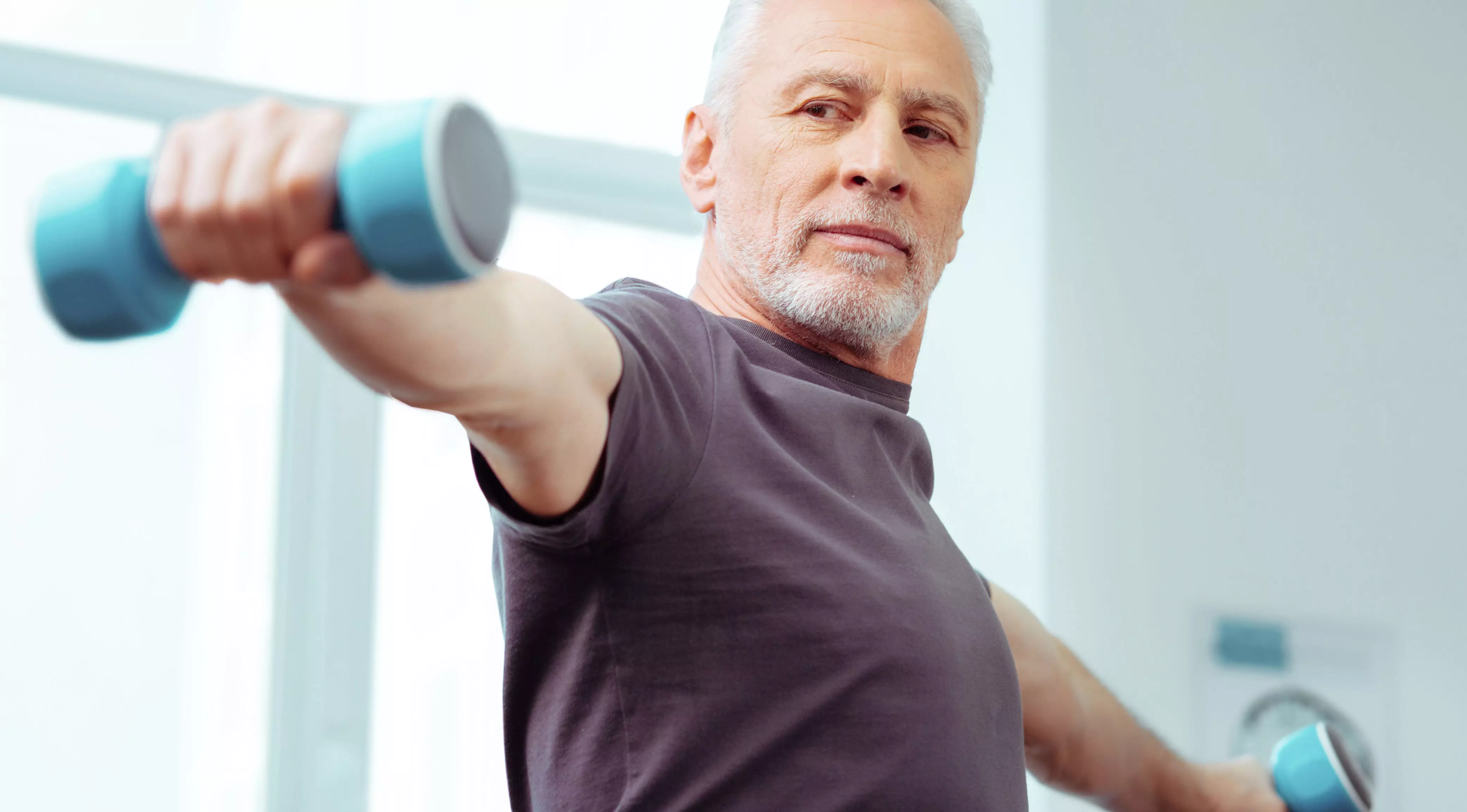 Ouder wordende man die bicepsoefeningen doet om fysieke achteruitgang om te keren