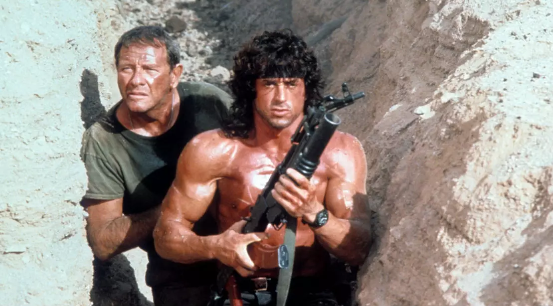 Sylvester Stallone hodi skozi jarek z Richardom Crenno v prizoru iz filma 'Rambo III', 1988. (Fotografija TriStar/Getty Images)