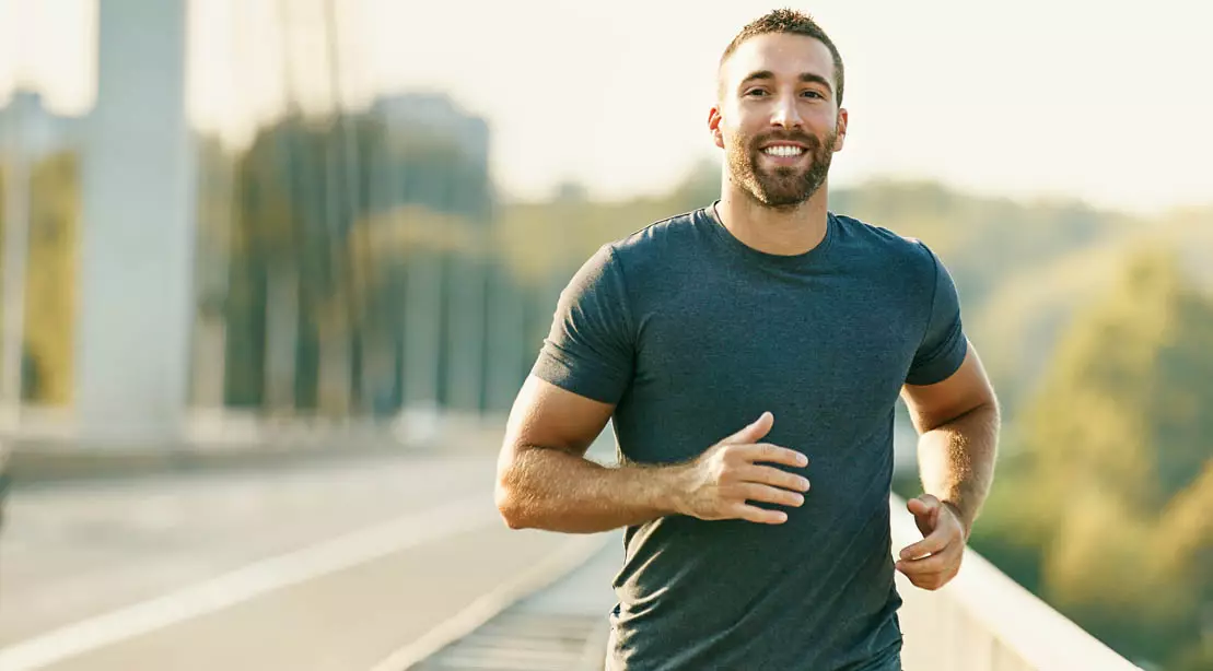 Fitter glücklicher Mann über 40, der draußen läuft und lächelt