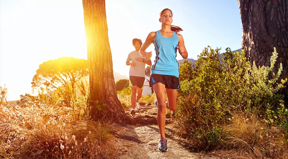 Mulher correndo por uma trilha de montanha e treinando para uma maratona e saúde mental mais forte