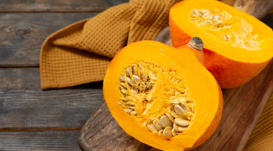 Citrouille coupée en deux sur une planche de bois