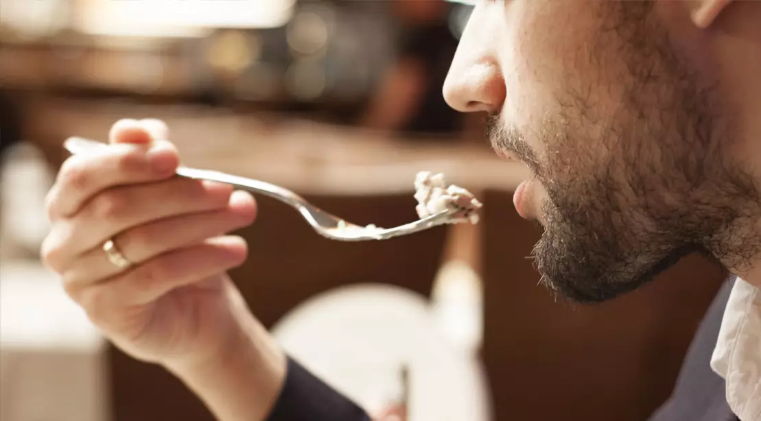 Hungrig man som äter tonfisk med en gaffel