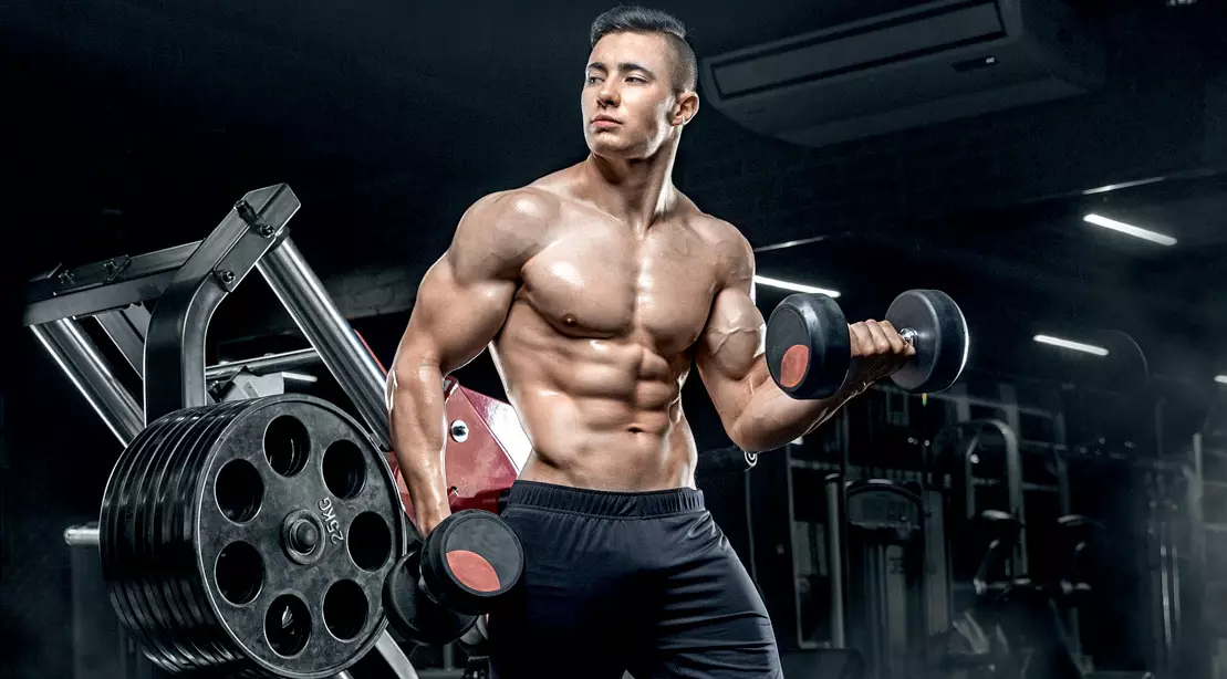 Model kebugaran otot ramping melakukan dumbbell bicep curls untuk mendapatkan tubuhnya ramping dan berotot