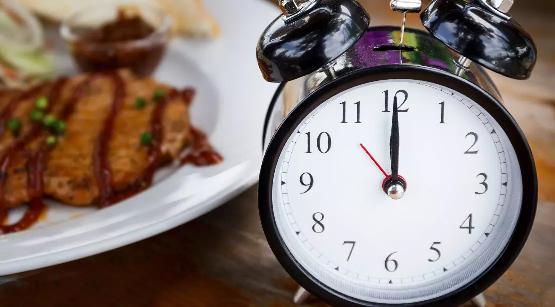 Alarm clock sa tabi ng dinner plate na may steak