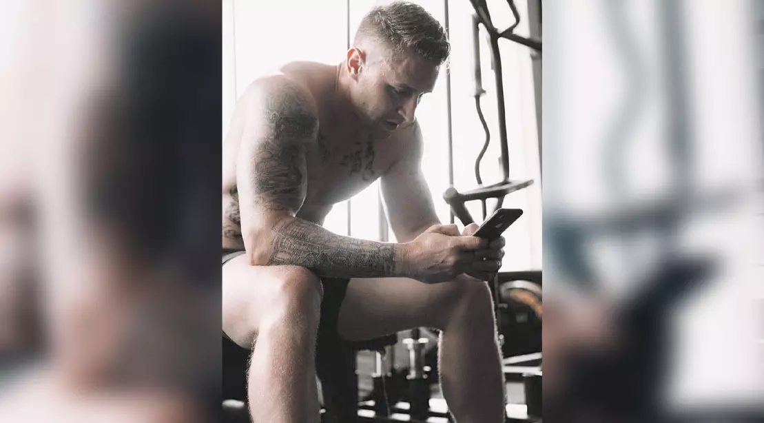 Erik Bartell topless pe telefonul său inteligent verificându-și cei 150.000 de urmăritori pe Instagram