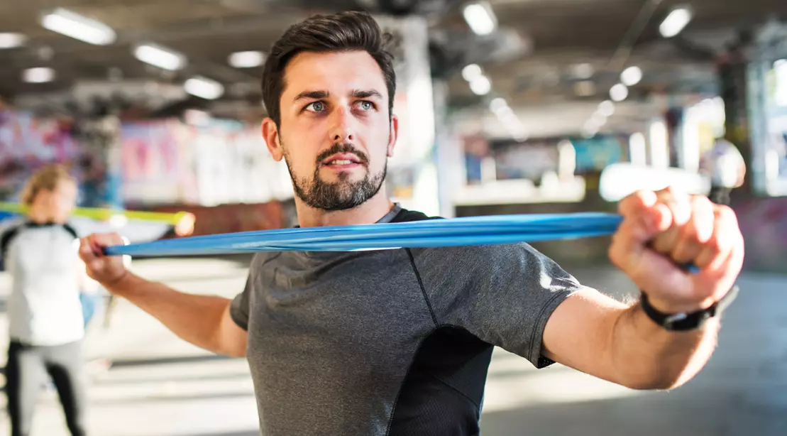 Fikse man wat oefen met 'n band-oefensessie in die gimnasium