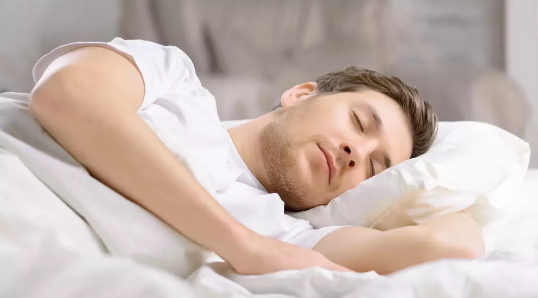 白いシーツのベッドで安らかに眠っている男。